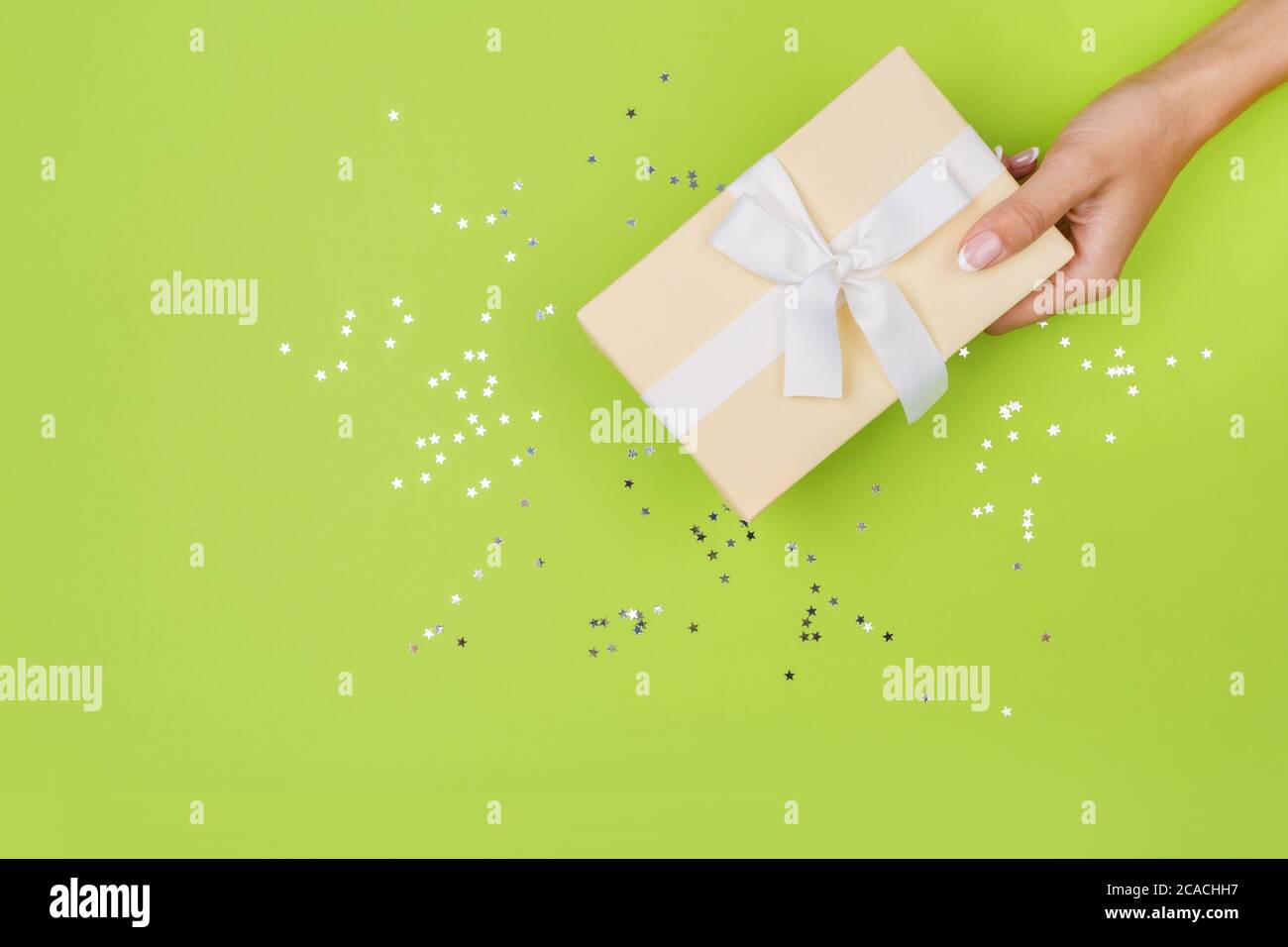 Women hands holding a gift or gift box decorated with confetti on a green table top view Stock ...
