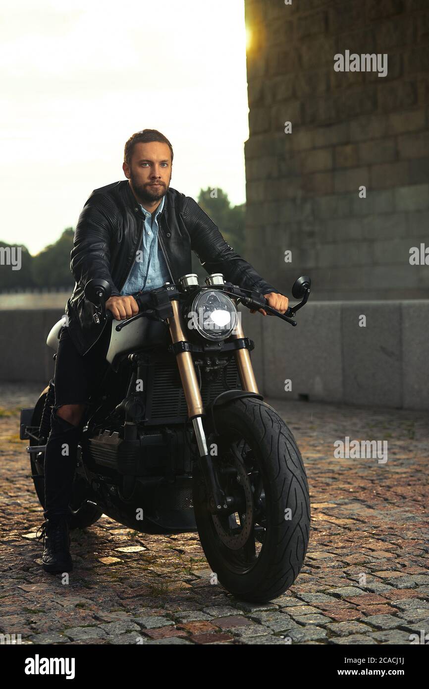 Stylish fashionable biker dressed in a black leather jacket sitting on ...
