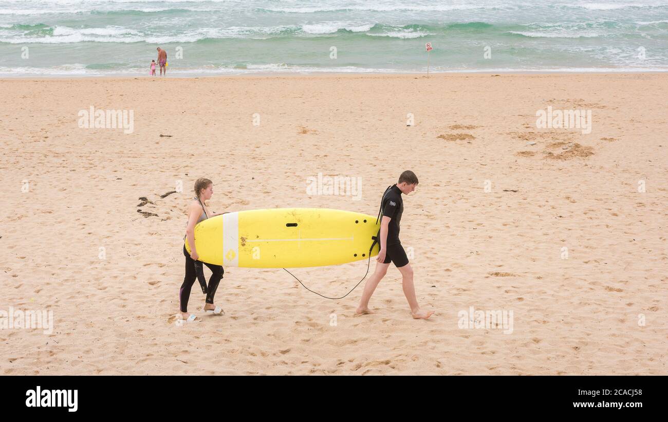 A panoramic image of holidaymakers carrying their hired surfboard on ...