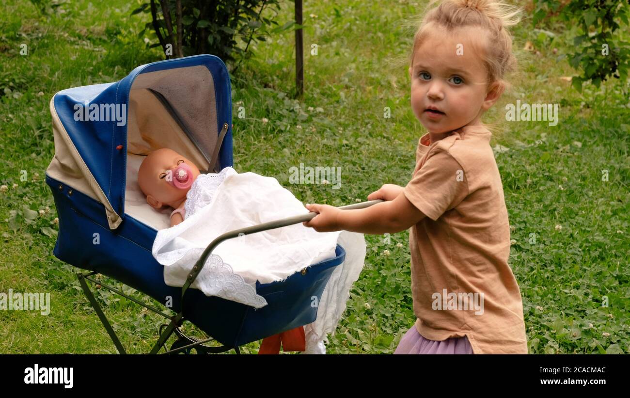 Cute little girl with her toy carriage Stock Photo - Alamy