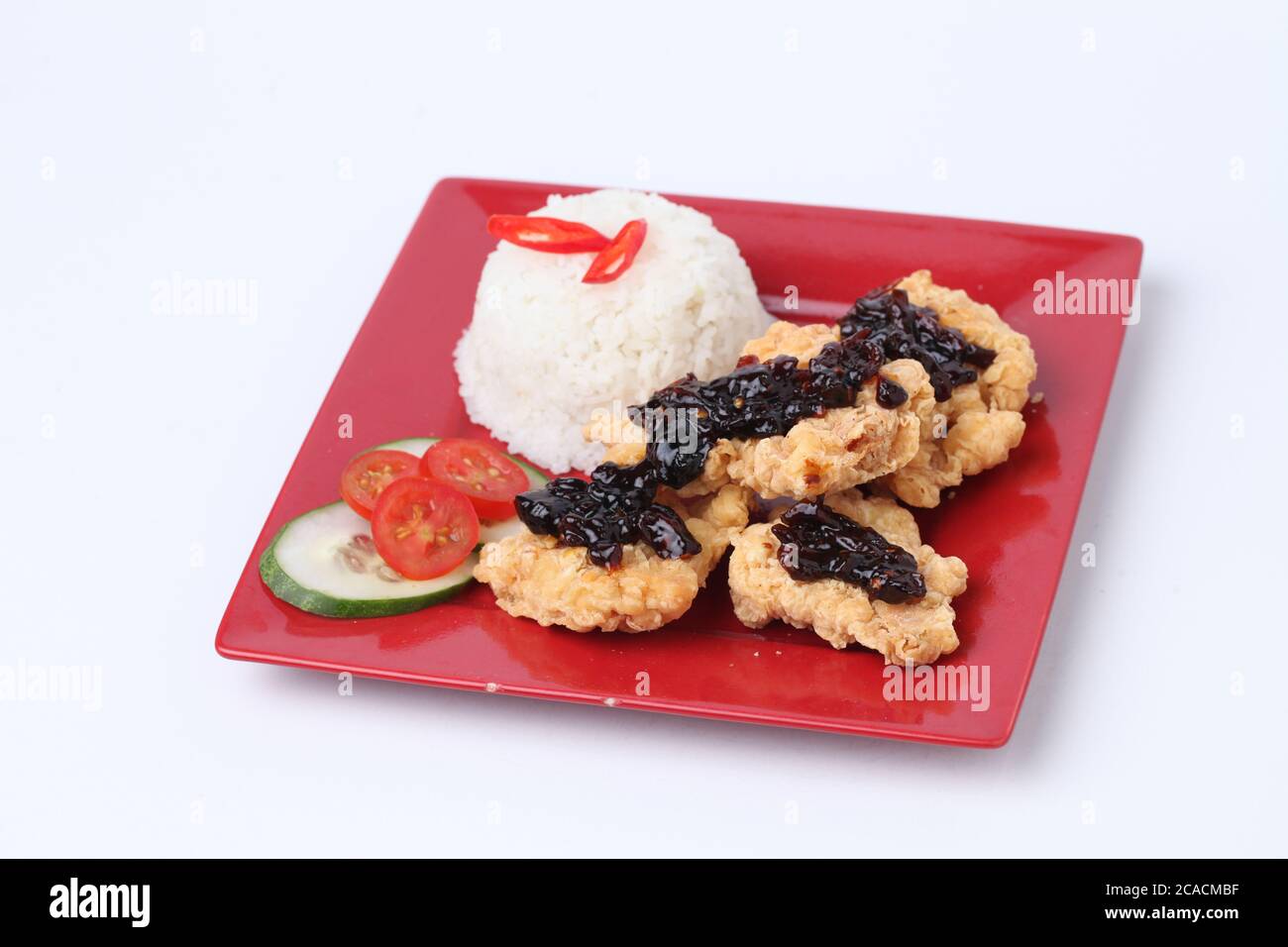 Fried chicken and rice on a red plate with black spicy flavor isolated ...