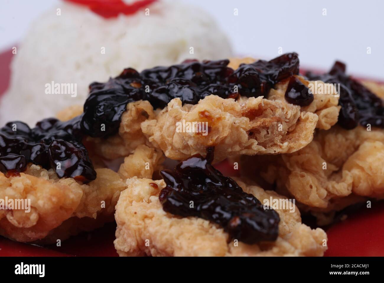 Fried chicken and rice on a red plate with black spicy flavor isolated ...