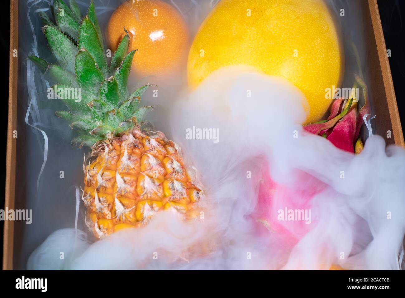 Wooden box with different exotic fruits in smoke Stock Photo - Alamy
