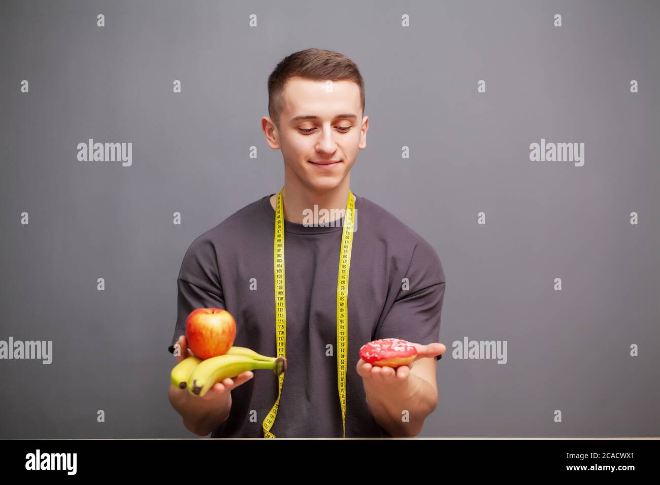 Shaped and healthy body man holding a fresh fruits and junk food Stock ...