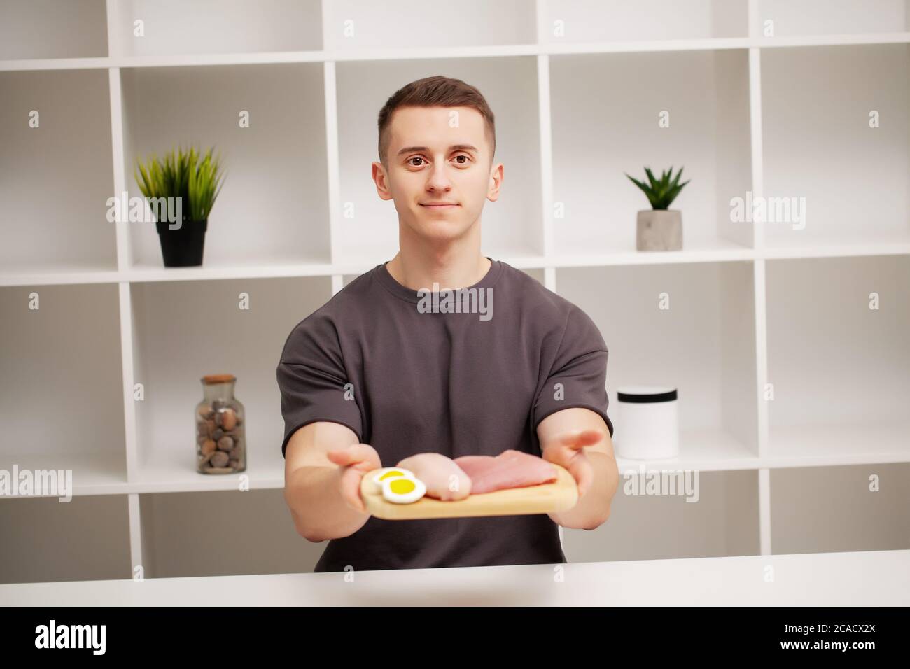 Shaped and healthy man holding a fresh meal board with meat Stock Photo ...