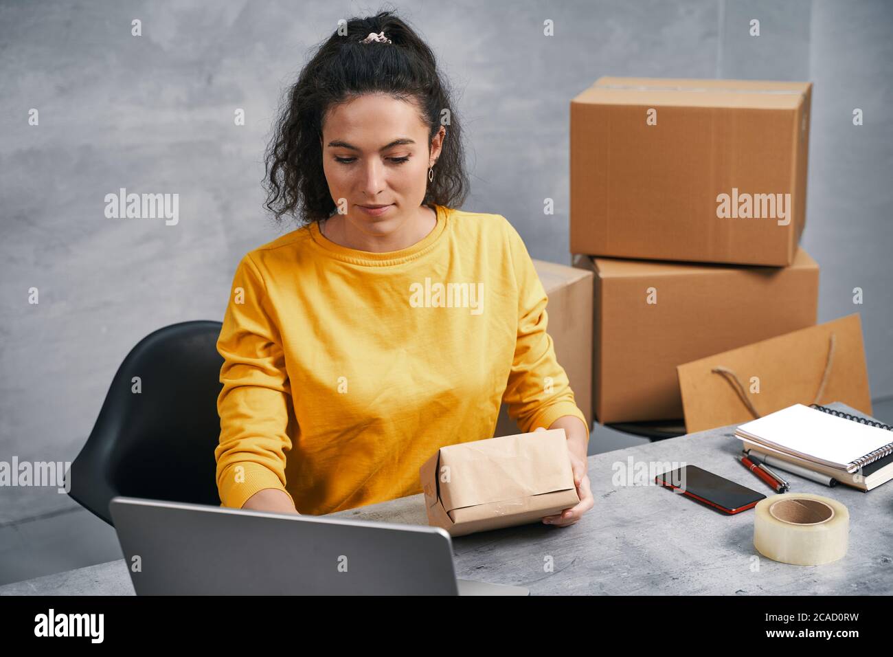 Woman sending parcel using her laptop. Working from home Stock Photo ...