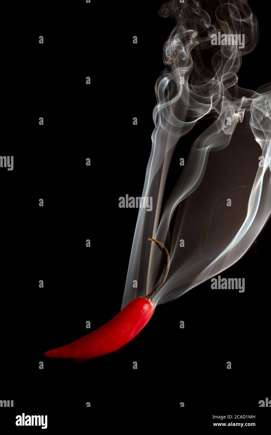 Red pepper pouring smoke on black background Stock Photo - Alamy
