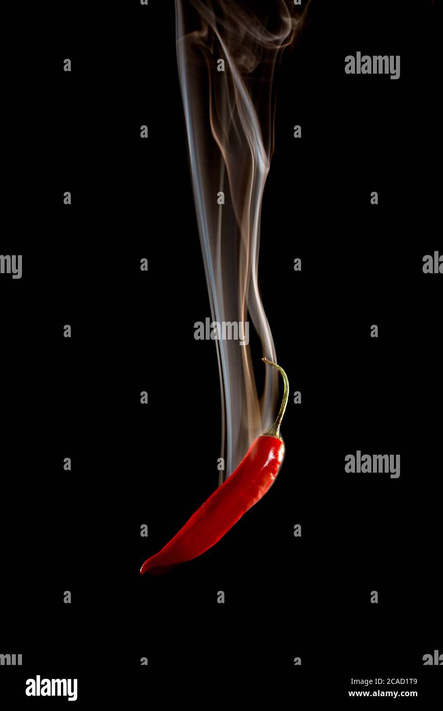 Red pepper pouring smoke on black background Stock Photo - Alamy