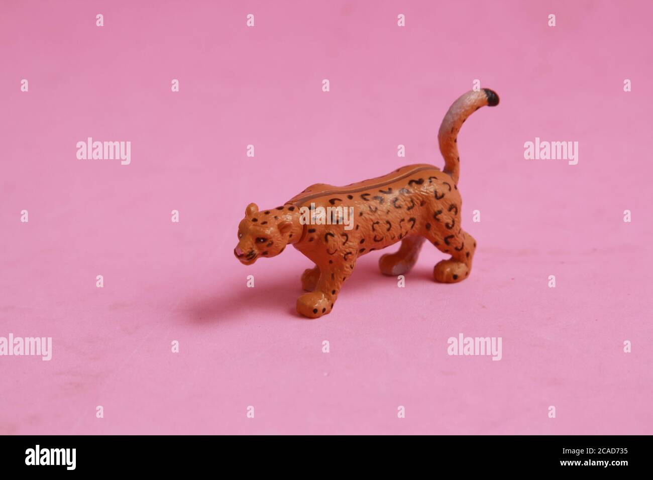 Small leopard plastic toy on a pink background Stock Photo - Alamy