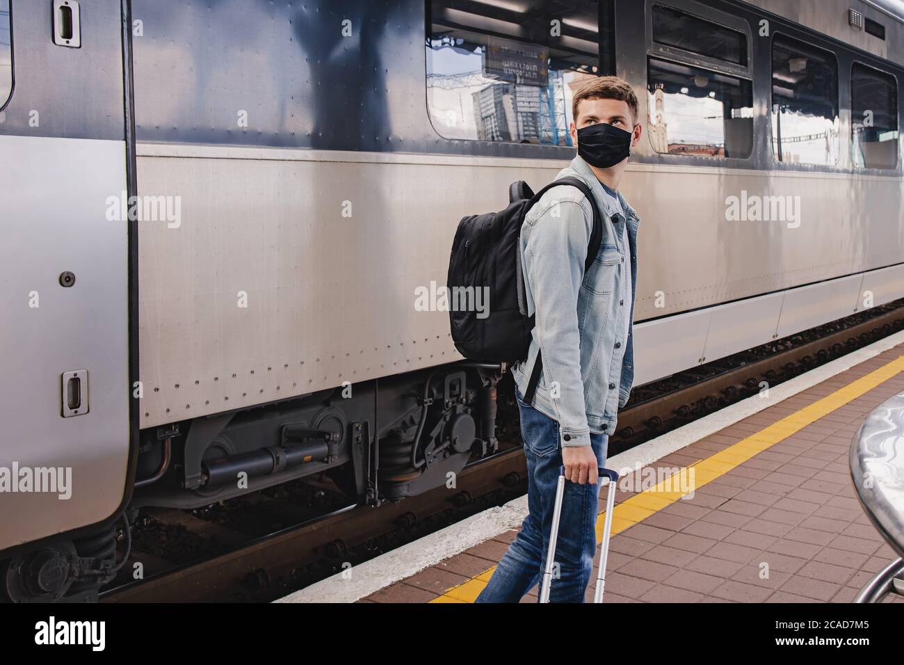 Young man wearing protective face mask standing on the railway station ...