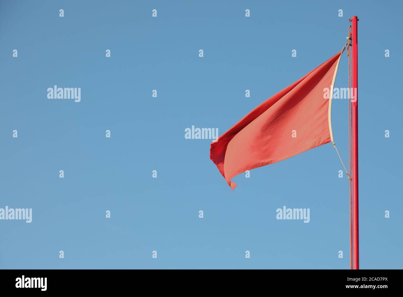 red flag indicating a dangerous situation on the background of the blue ...