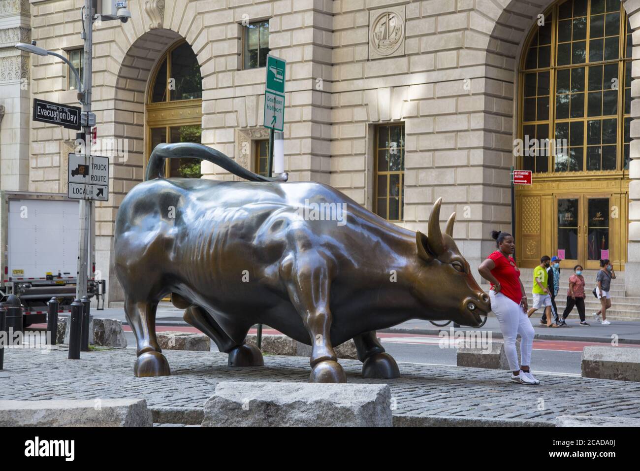 Tourist poses in fron of the famous Wall Street Bronze Bull on Broadway ...