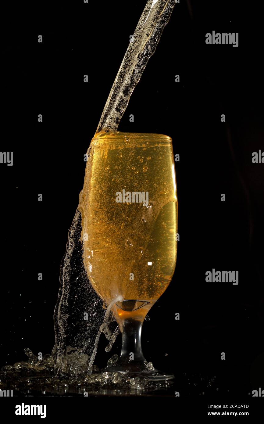 Beer falling into a glass and forming a splash on a black background ...