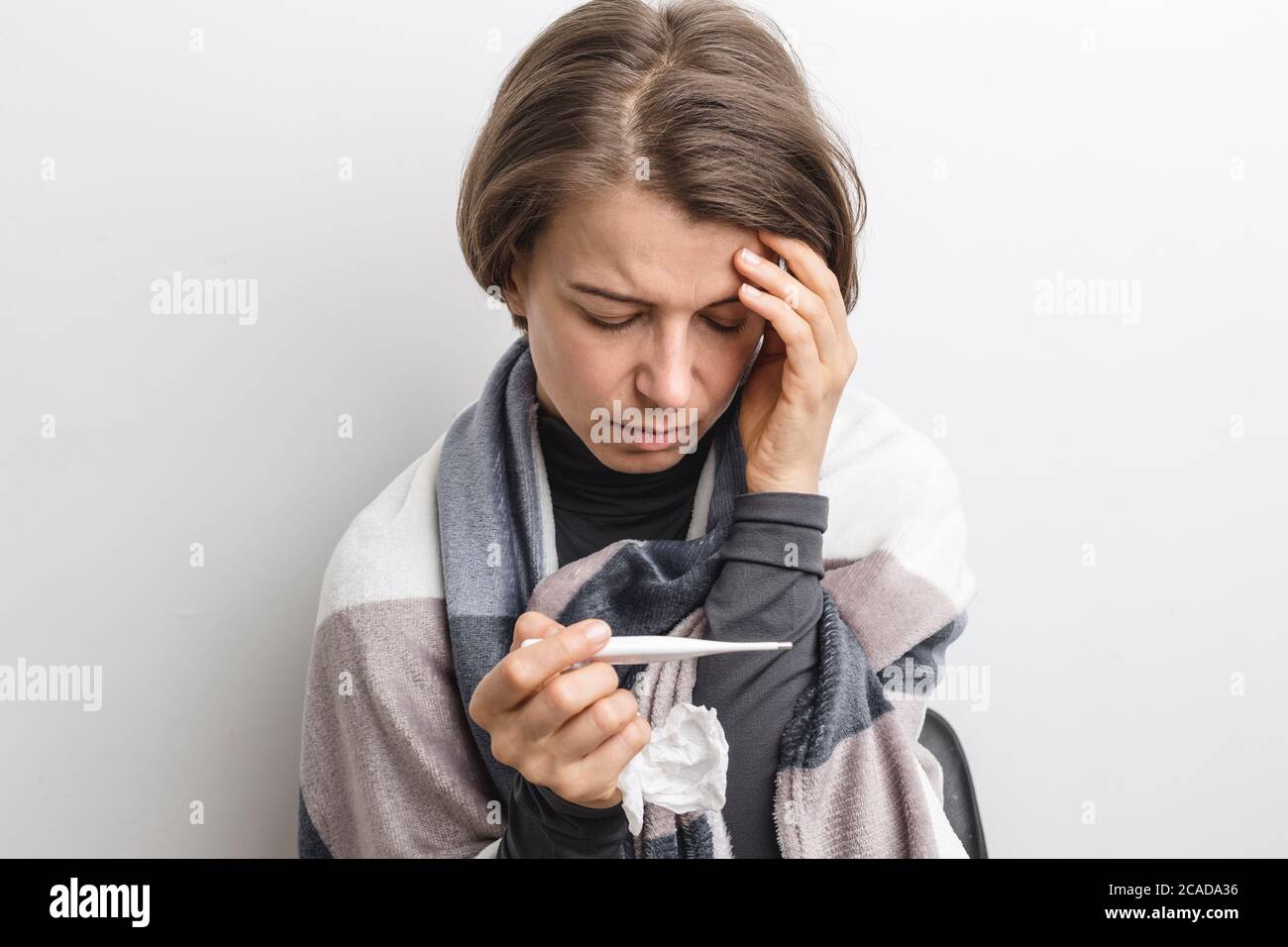 A sick, cold woman measures her temperature with a thermometer Stock ...
