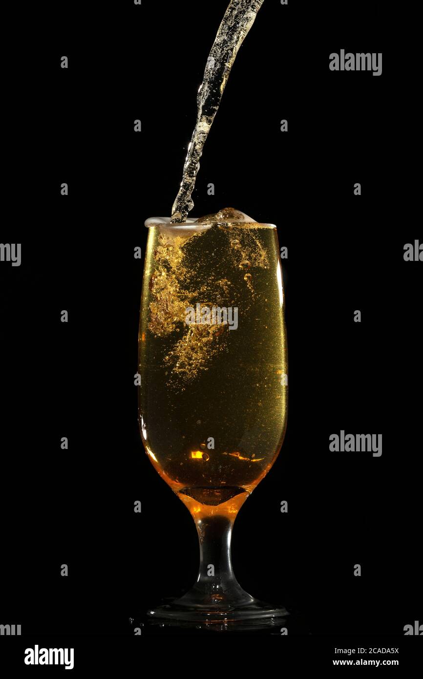 Beer falling into a glass and forming a splash on a black background ...