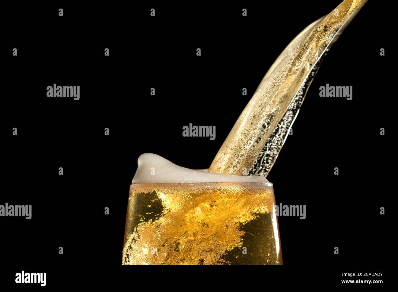 Beer falling into a glass and forming a splash on a black background ...