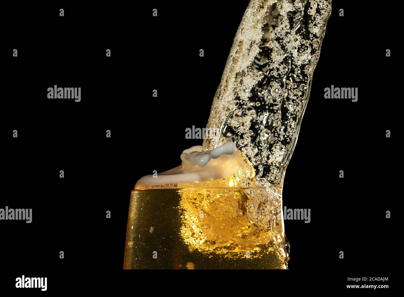 Beer falling into a glass and forming a splash on a black background ...