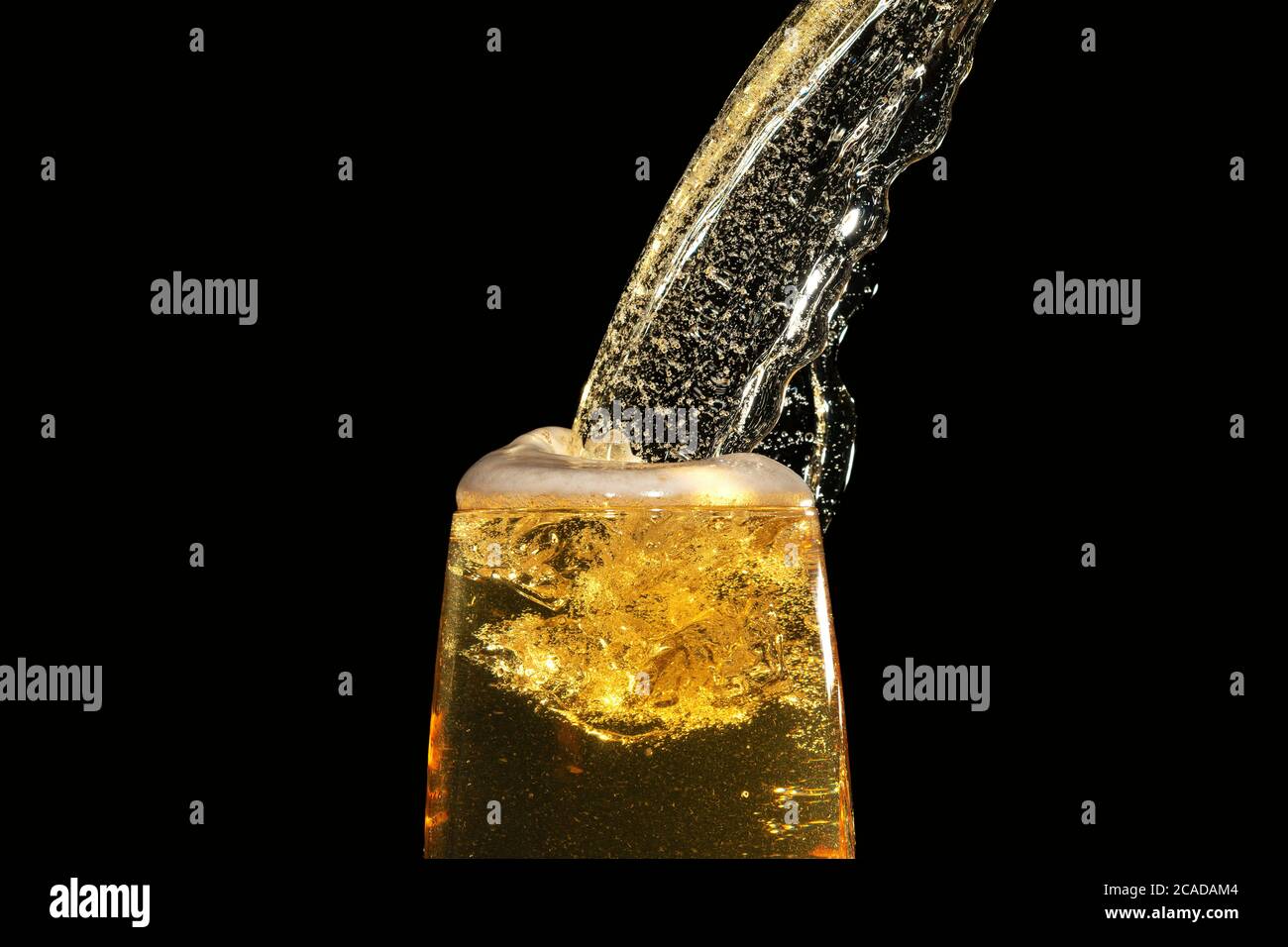 Beer falling into a glass and forming a splash on a black background ...