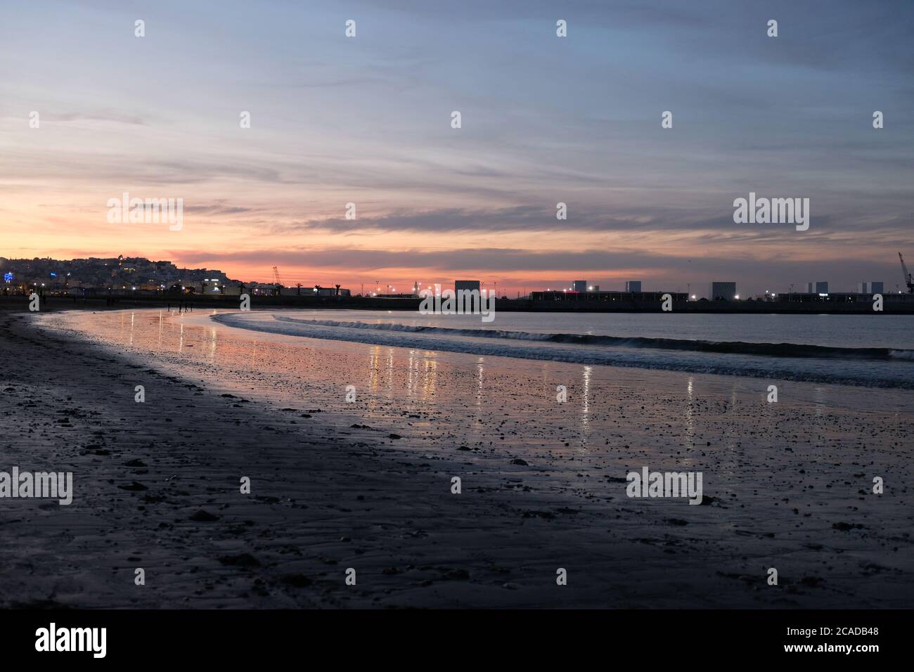perspective view of wide beach and sea waves under colorful sunset. In ...