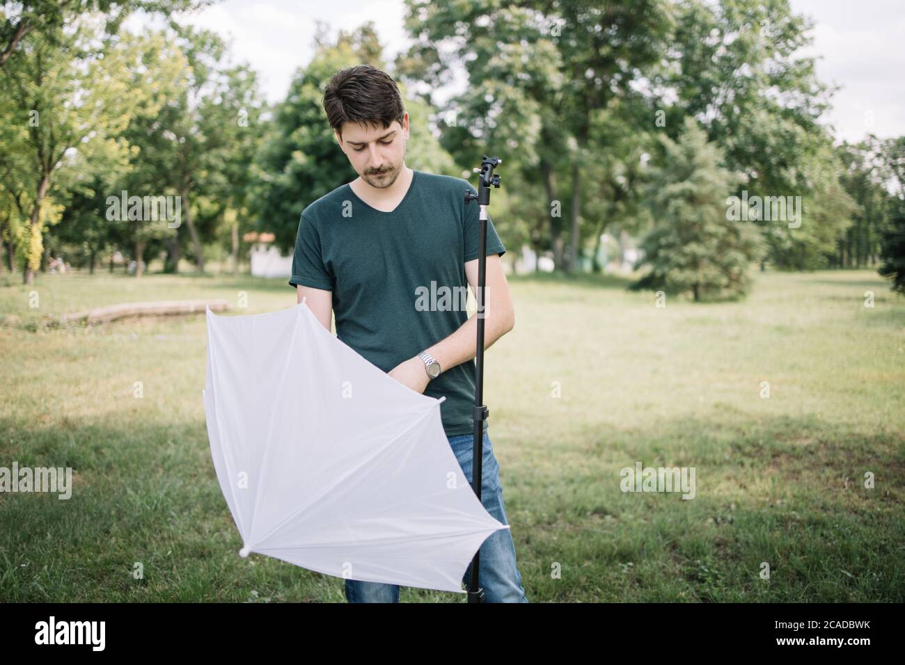 Young male photographer setting umbrella diffuser outdoor Stock Photo ...