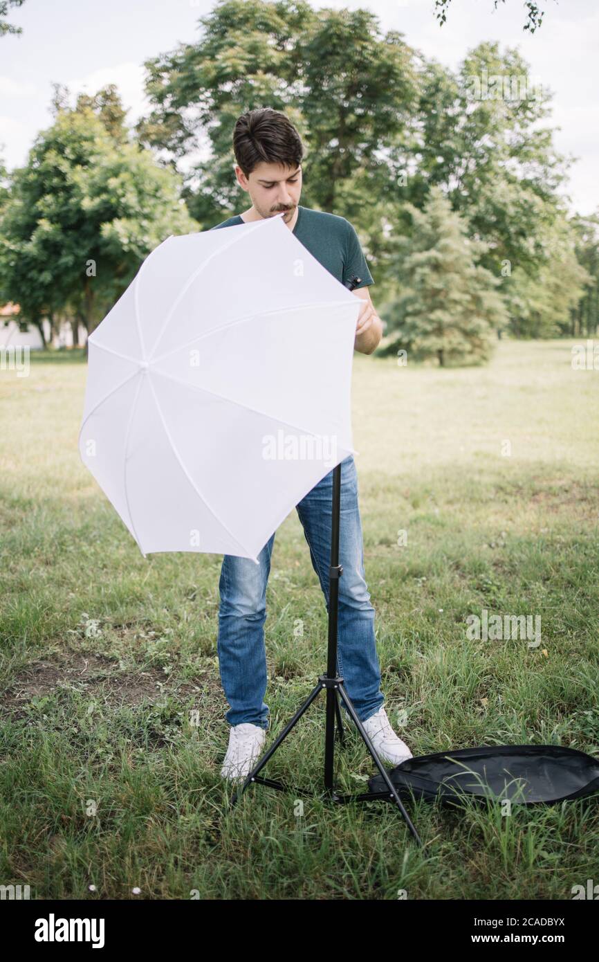 Male photographer setting umbrella diffuser for making outdoor photo ...