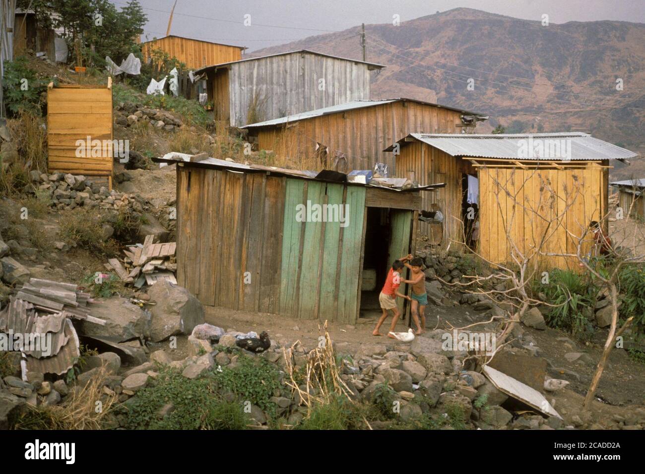 Children play in front of hillside shacks in Colonia Reycon, a poor ...