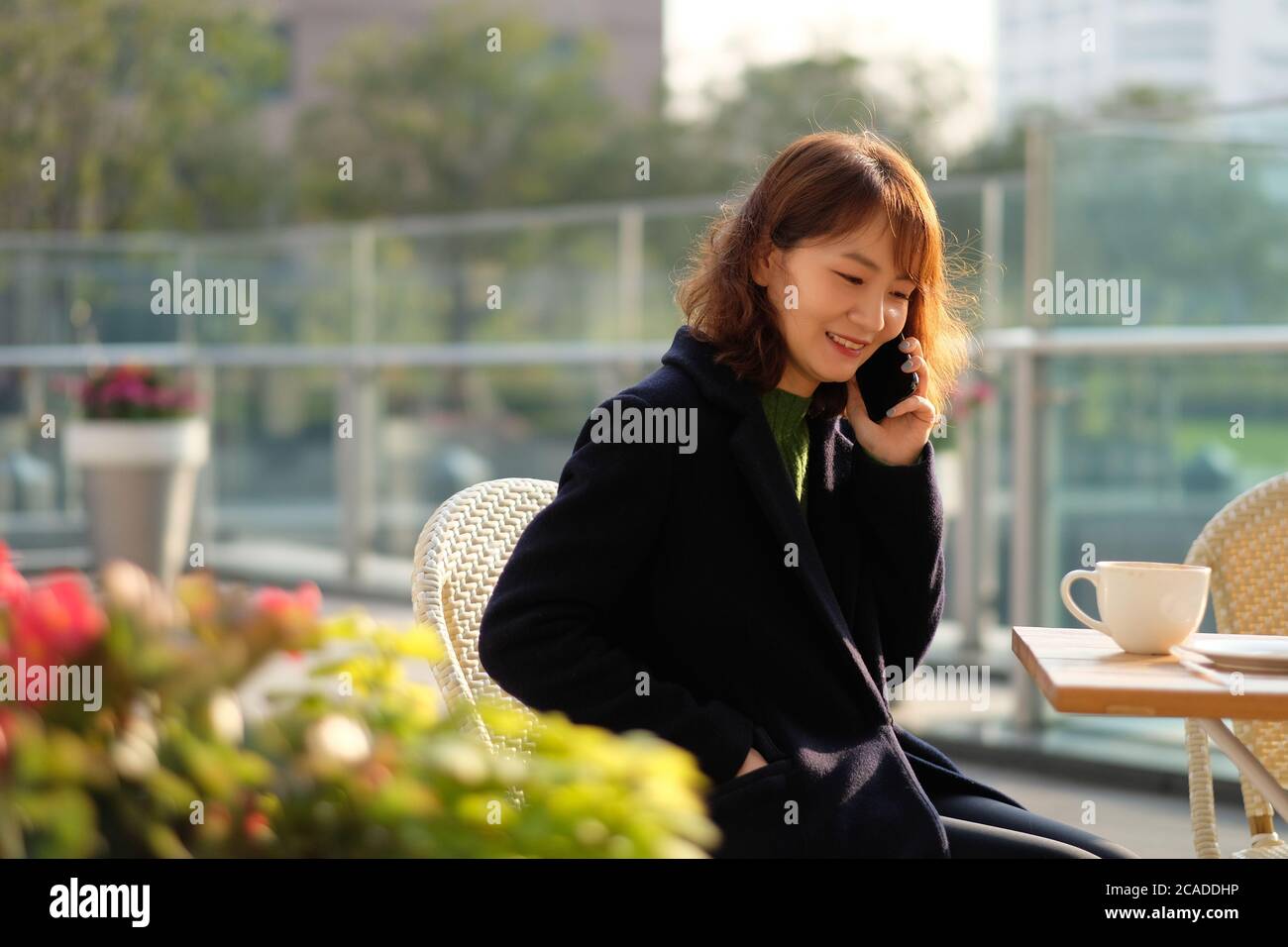 One Asian beautiful young woman sitting outdoor under sunshine,making ...