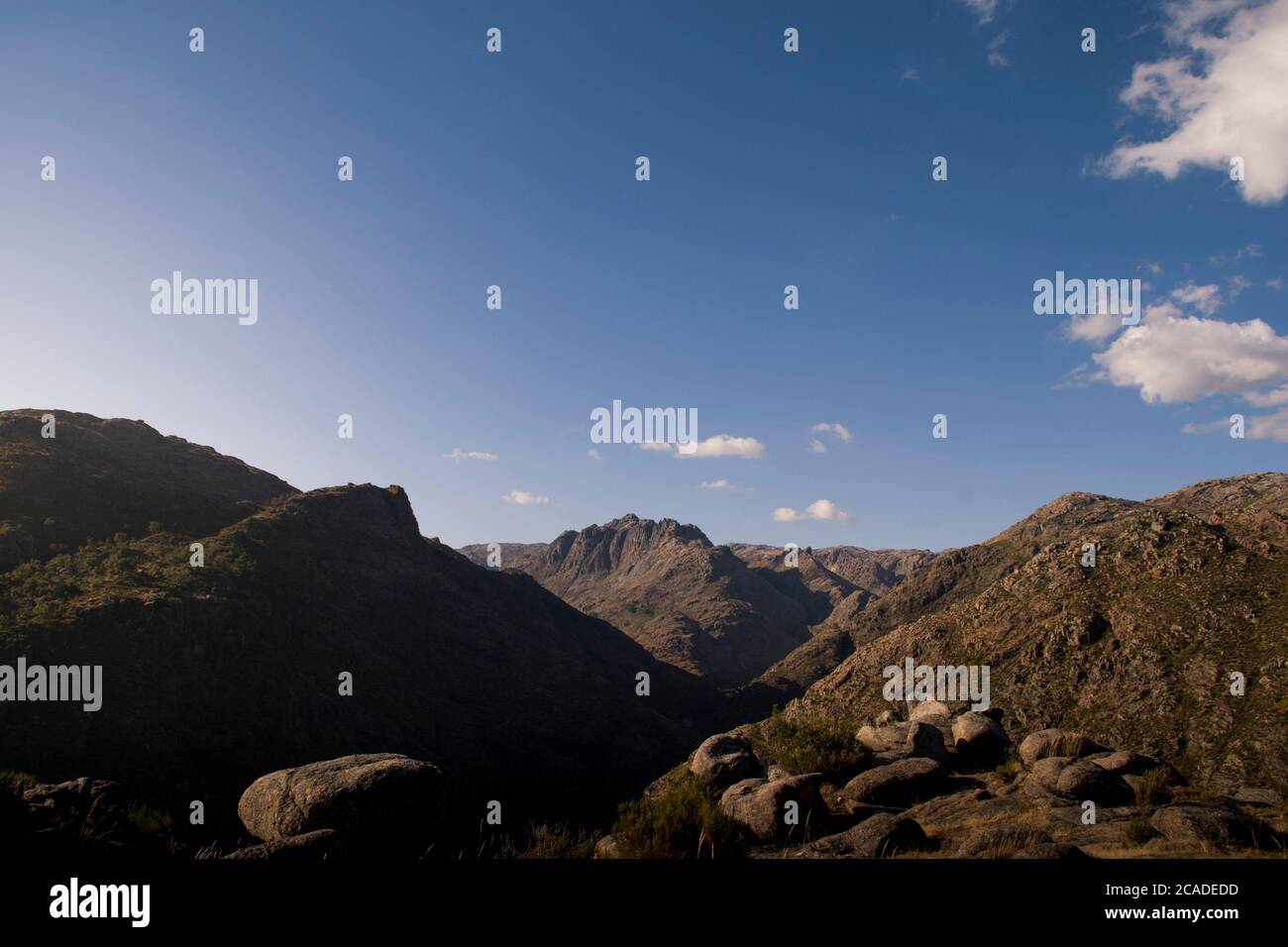 Mountain landscape with hard shadows on daylight and a bright blue sky ...