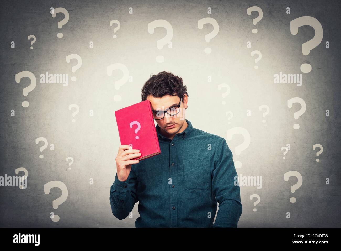 Confused student guy looks down upset, holding a book with question ...