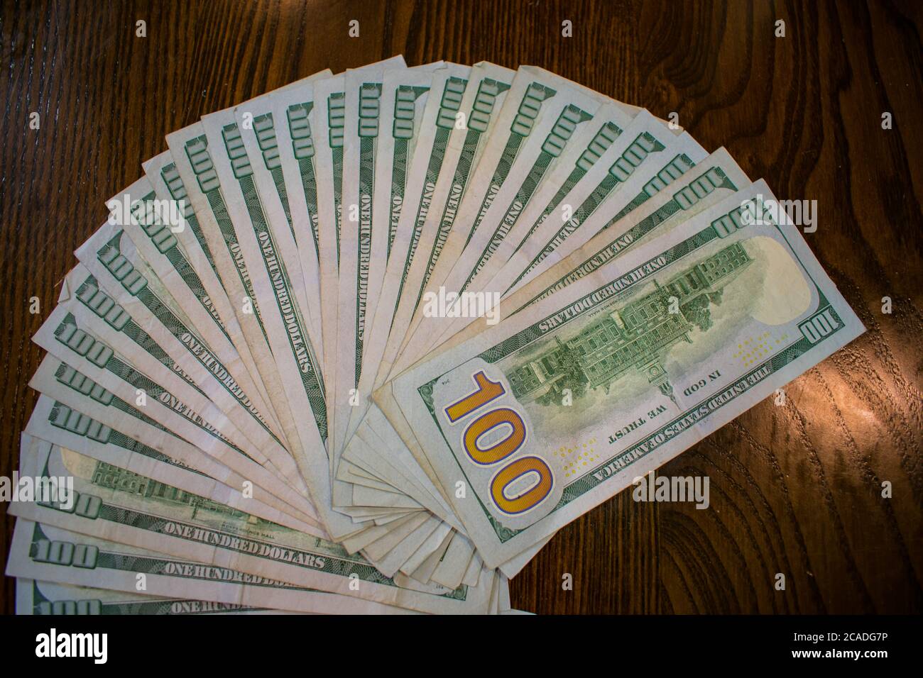 Fanned 100 dollar bills on a woden table Stock Photo - Alamy