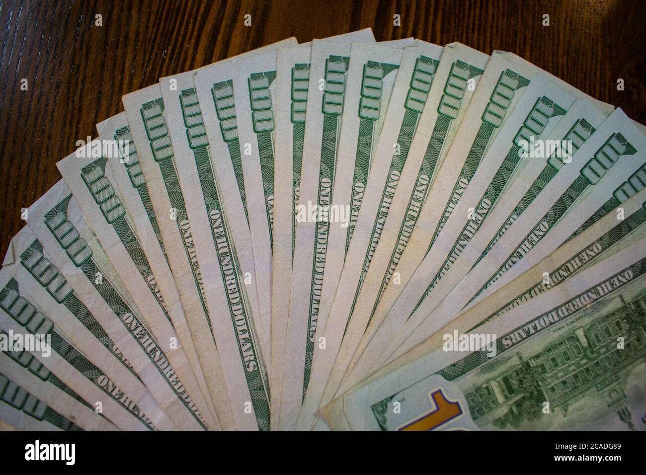 Fanned 100 dollar bills on a woden table Stock Photo - Alamy
