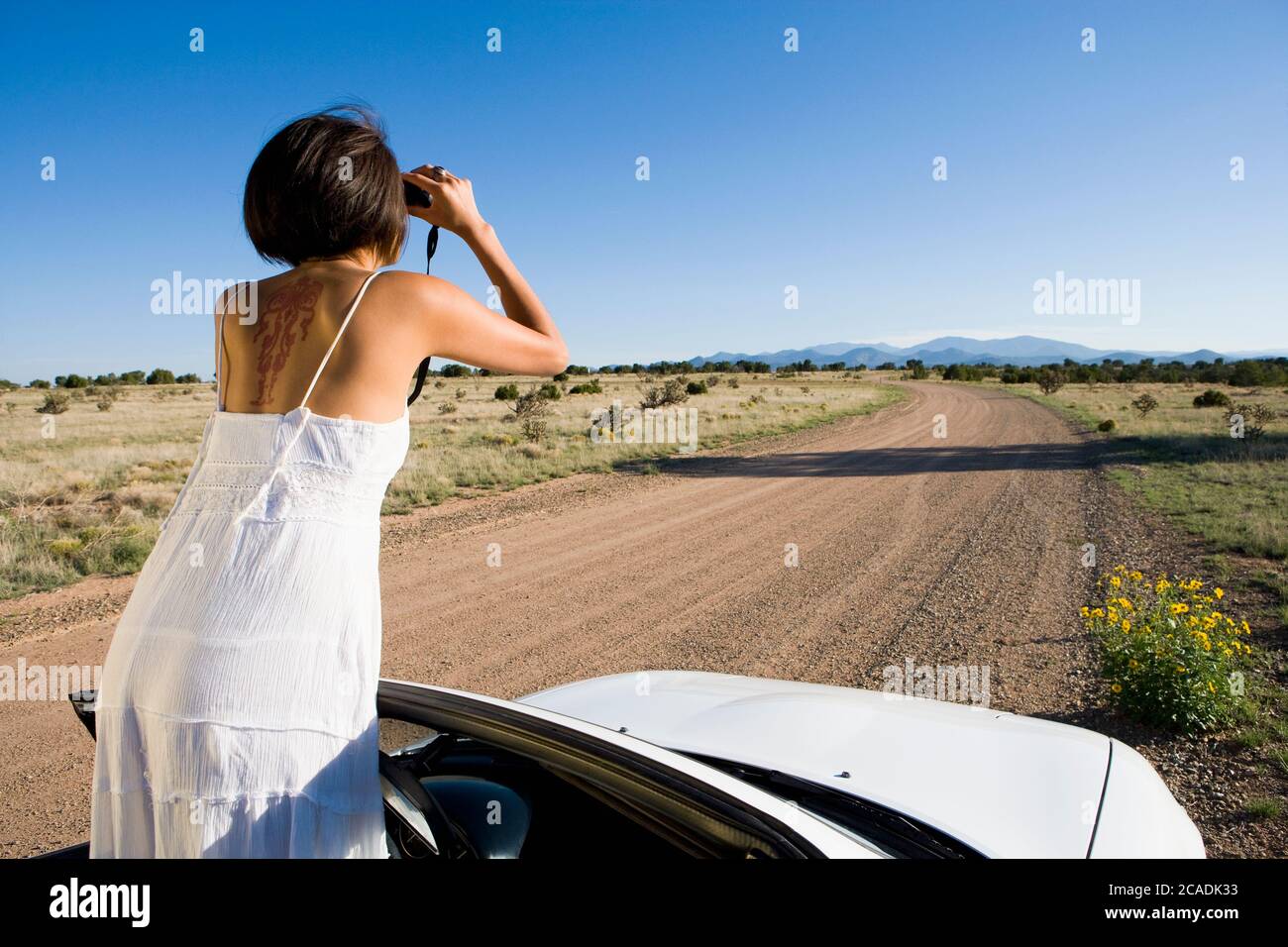 Native American woman in sun dress driving a white convertible sports ...
