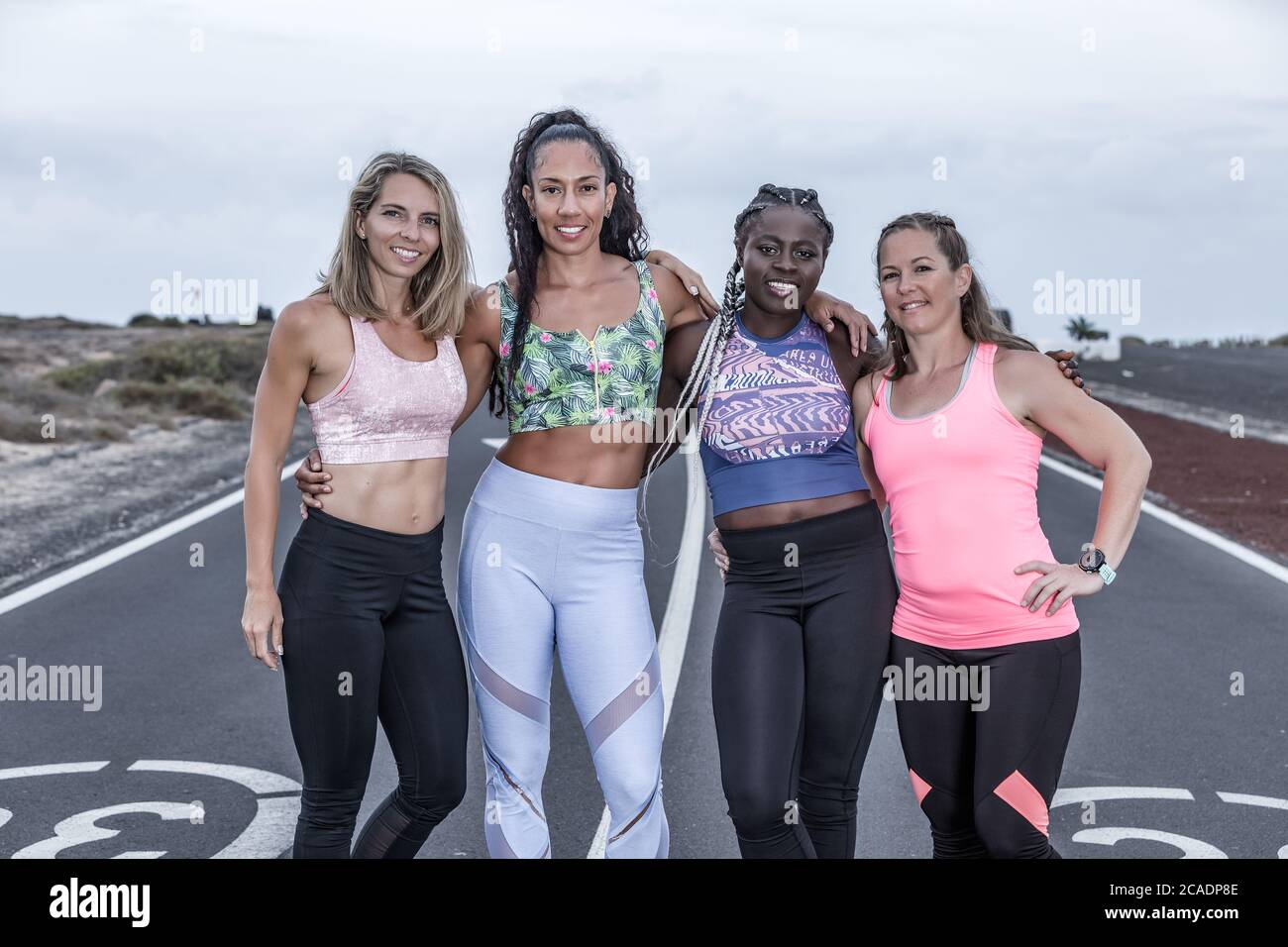 Group of cheerful multiethnic female athletes in sportswear hugging ...