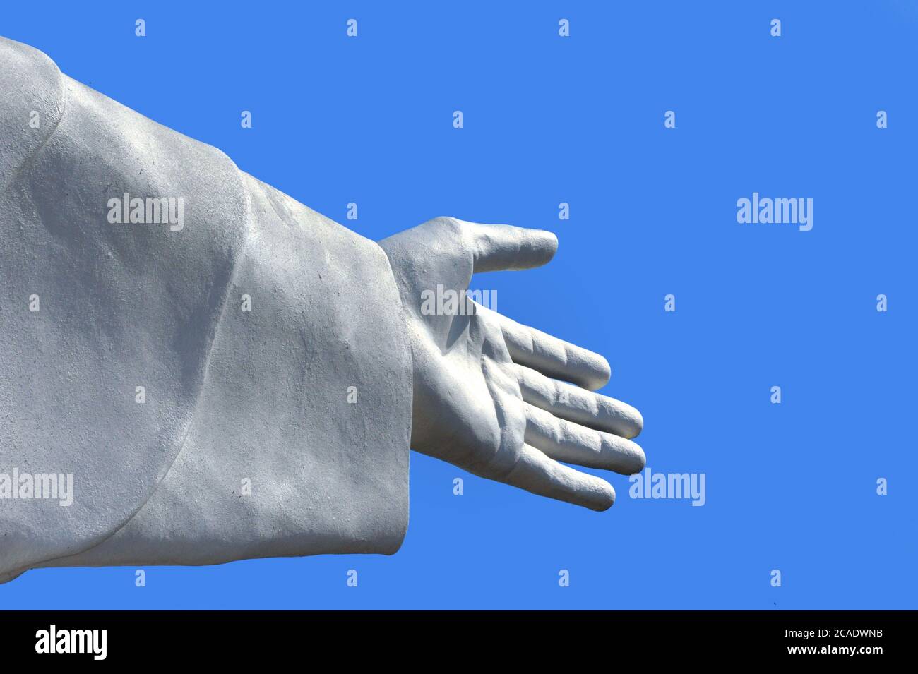 Statue has open hand, extended, reaching to help. Sky is vivid blue and ...