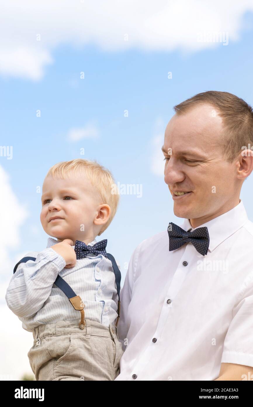 Father and son concept. Father carries child in his hands in blue sky ...