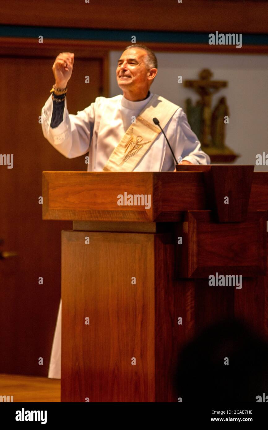 Wearing a white robe, an enthusiastic deacon preaches a sermon in the ...