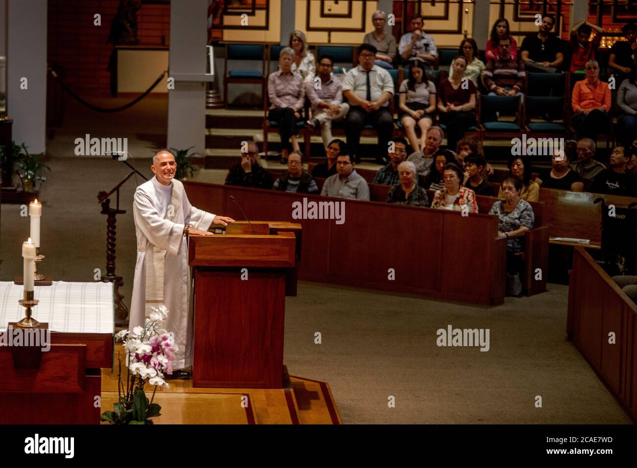 Wearing a white robe, an enthusiastic deacon preaches a sermon in the ...
