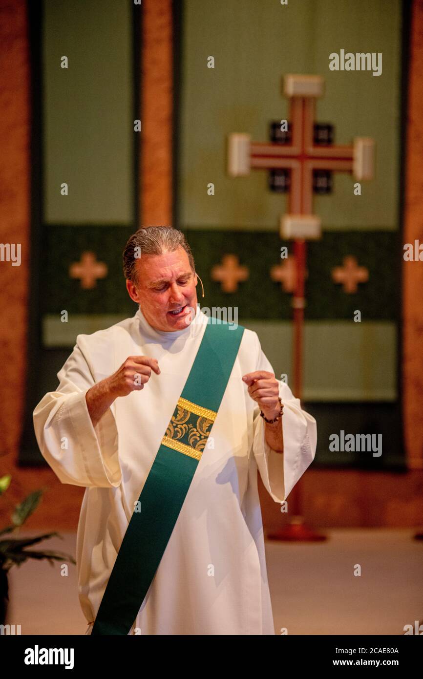 Wearing a white robe, an enthusiastic deacon preaches a sermon in the ...