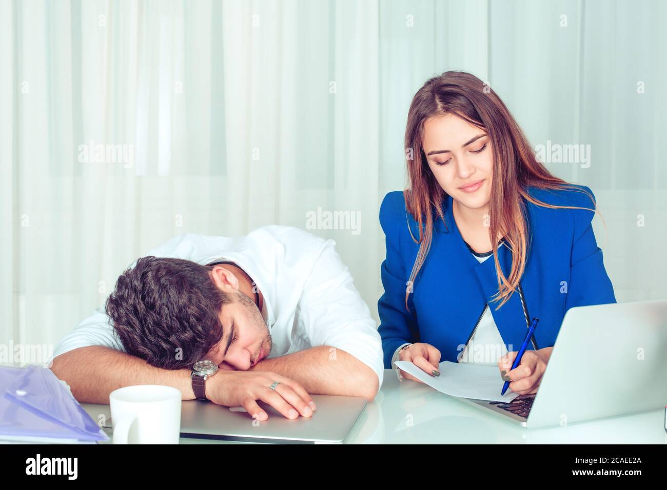 Bored lazy man sleeping at table with smart creative woman working ...