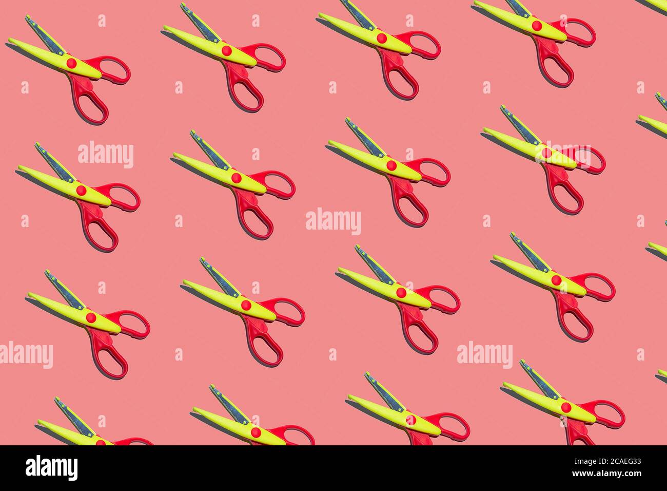 Open plastic yellow and red scissors on pastel pink color background ...