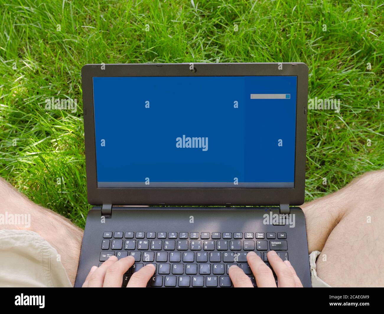 Laptop on man lap on the green grass Stock Photo - Alamy