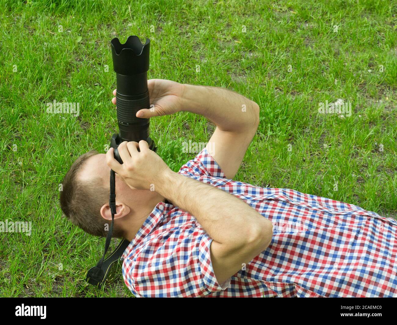 Photographer lies on the grass and takes pictures. Side view Stock ...