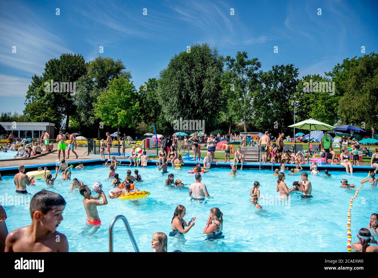 People at the outdoor pool enjoy the beautiful warm weather during a ...