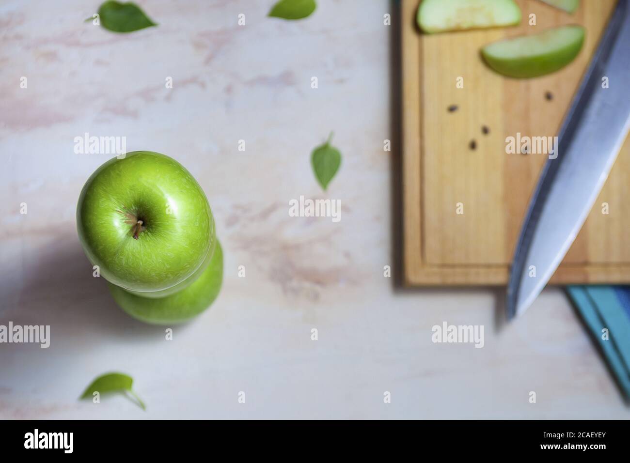 Top view of shining green apple next to blurred wooden cutting board ...
