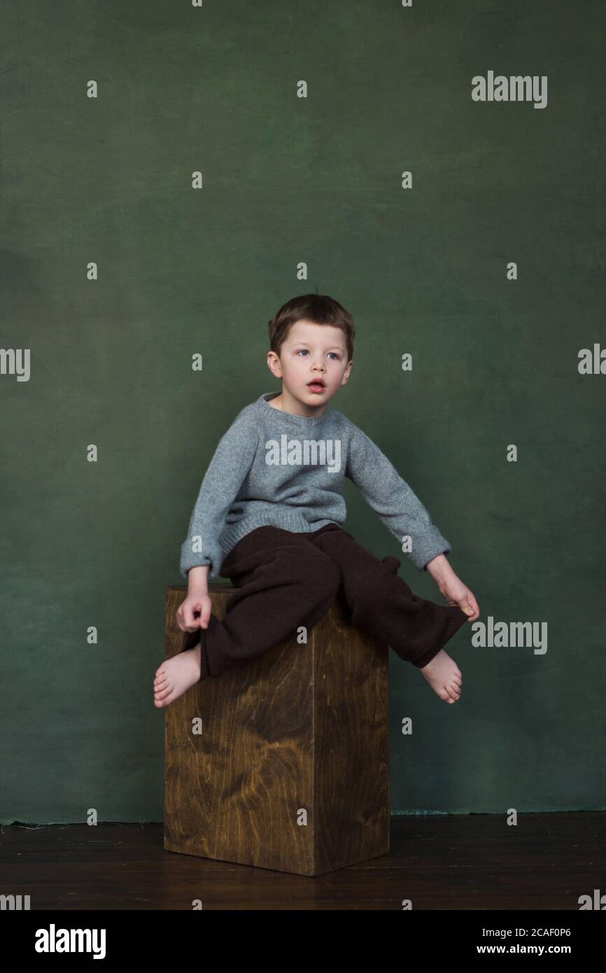 handsome boy sitting on wooden box, bewildered look, emotions of ...