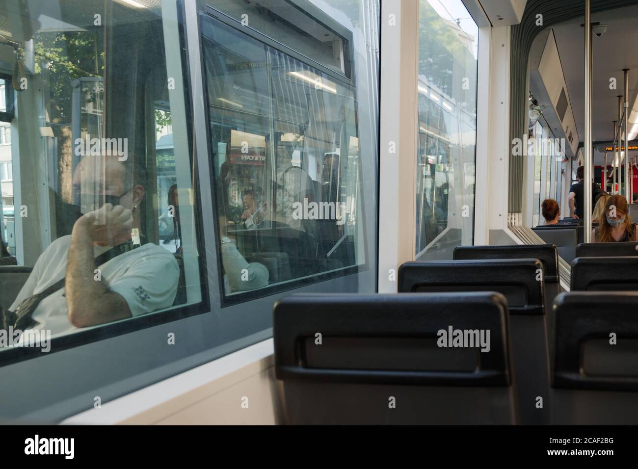 Caucasian passengers with face protection mask sit in light rail tram ...