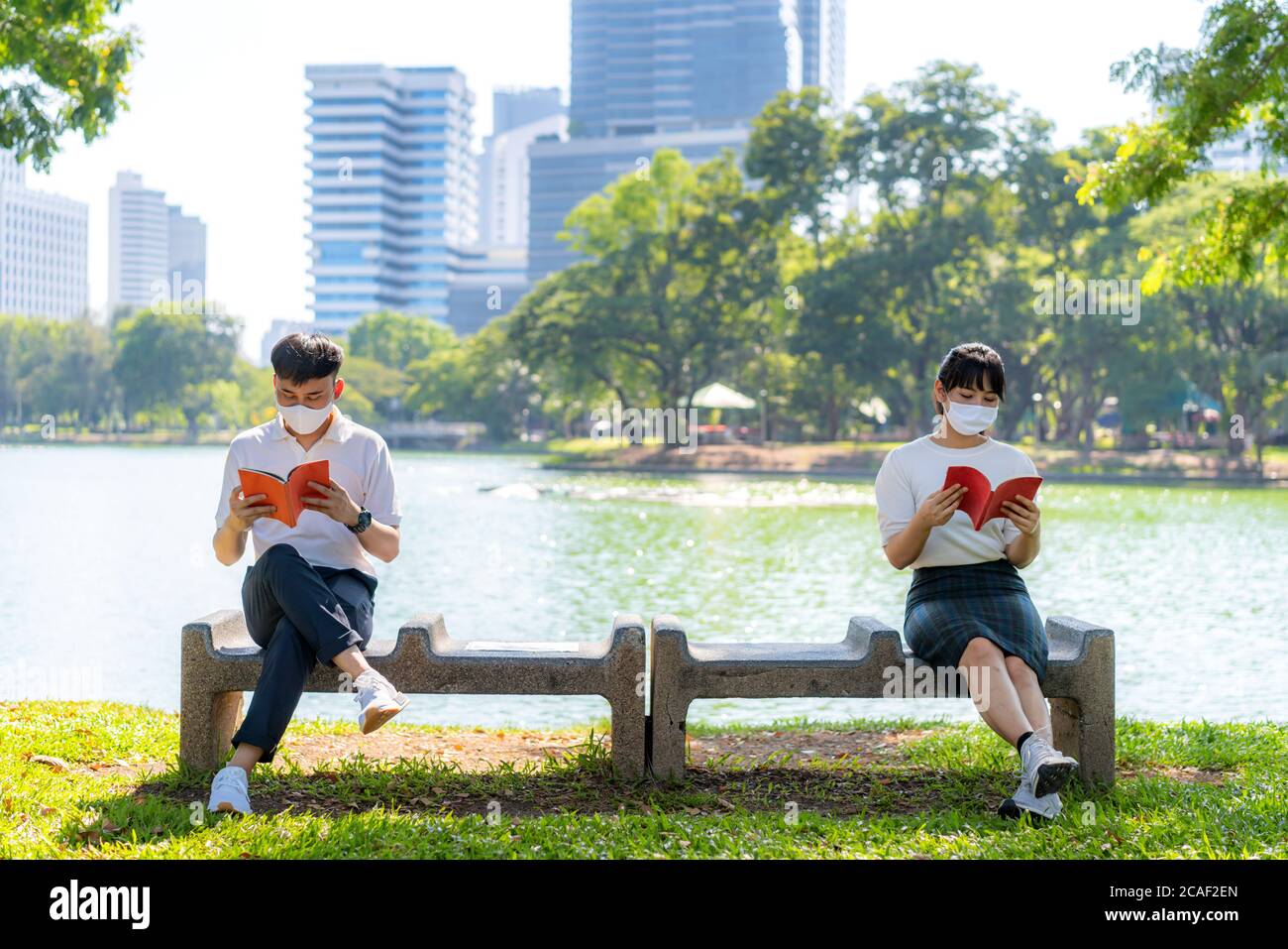 Asian young man and woman reading book and wearing mask sitting ...