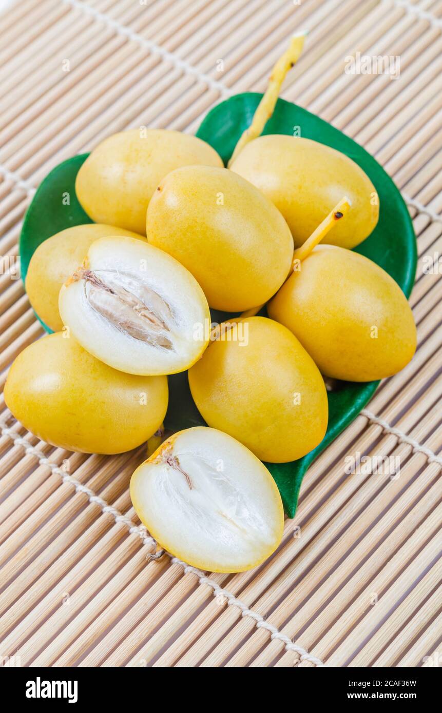 A bunch of fresh date palm fruits with green leaf on bamboo mat Stock ...