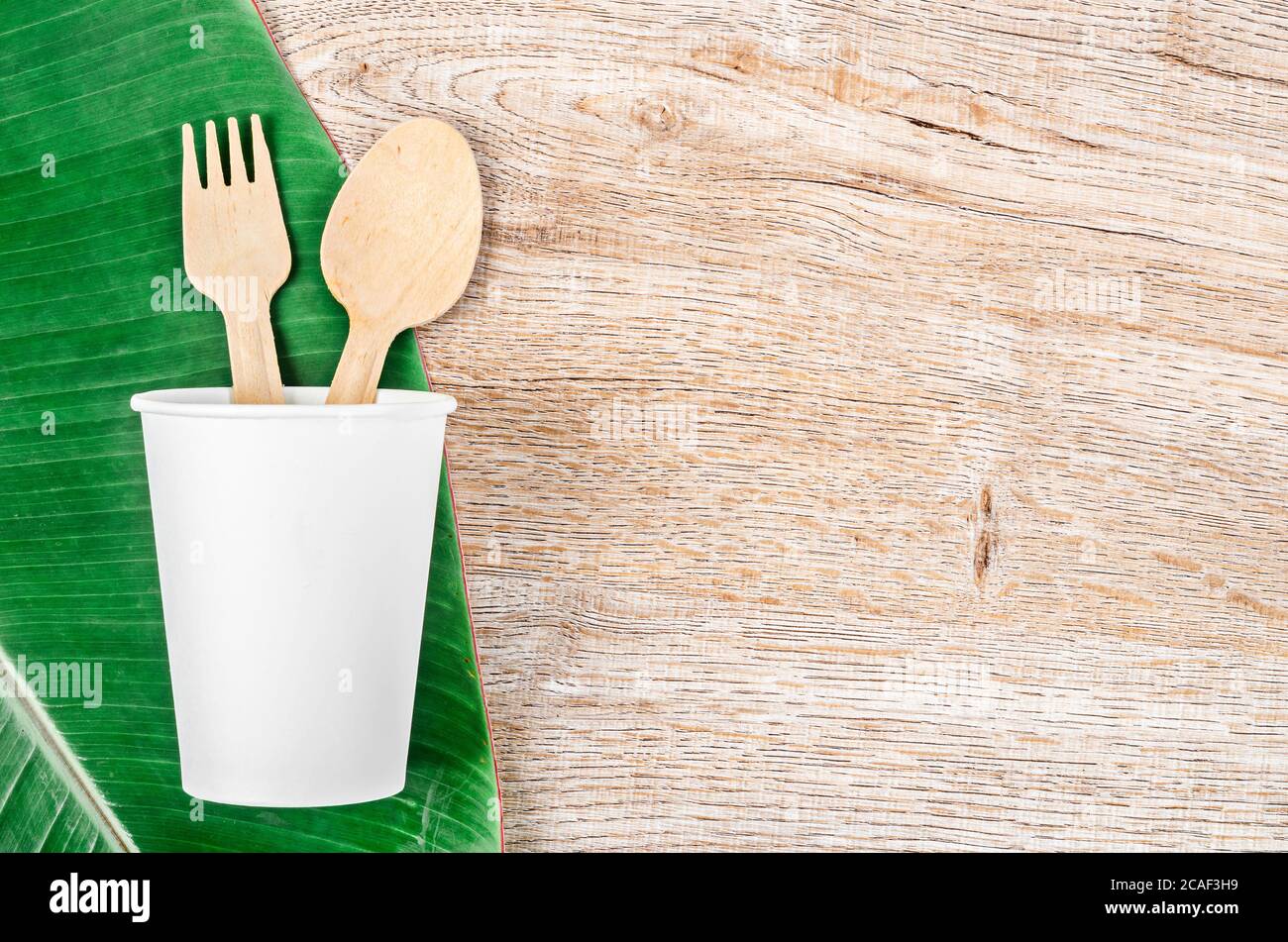 eco natural paper cups and wooden spoon with green leaf on wooden ...