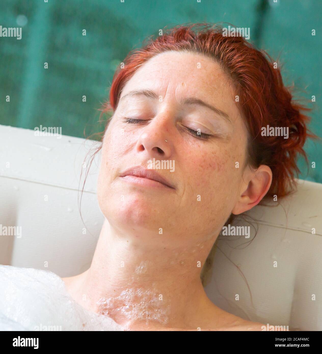Portrait of Pretty natural redheaded woman relaxing in her jacuzzi ...
